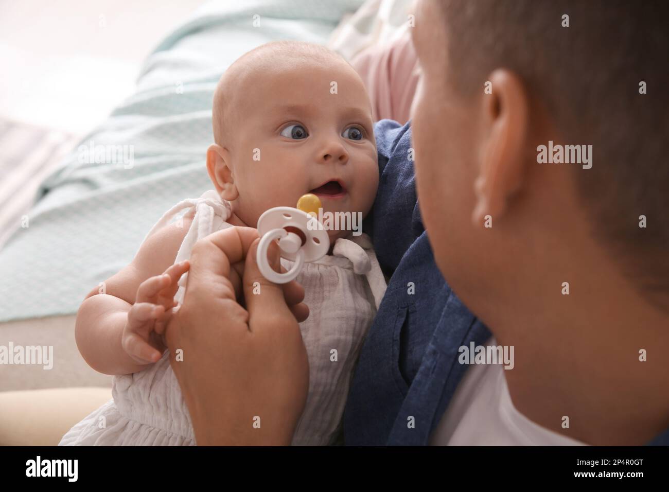 Father holding his cute little baby with pacifier at home Stock Photo ...