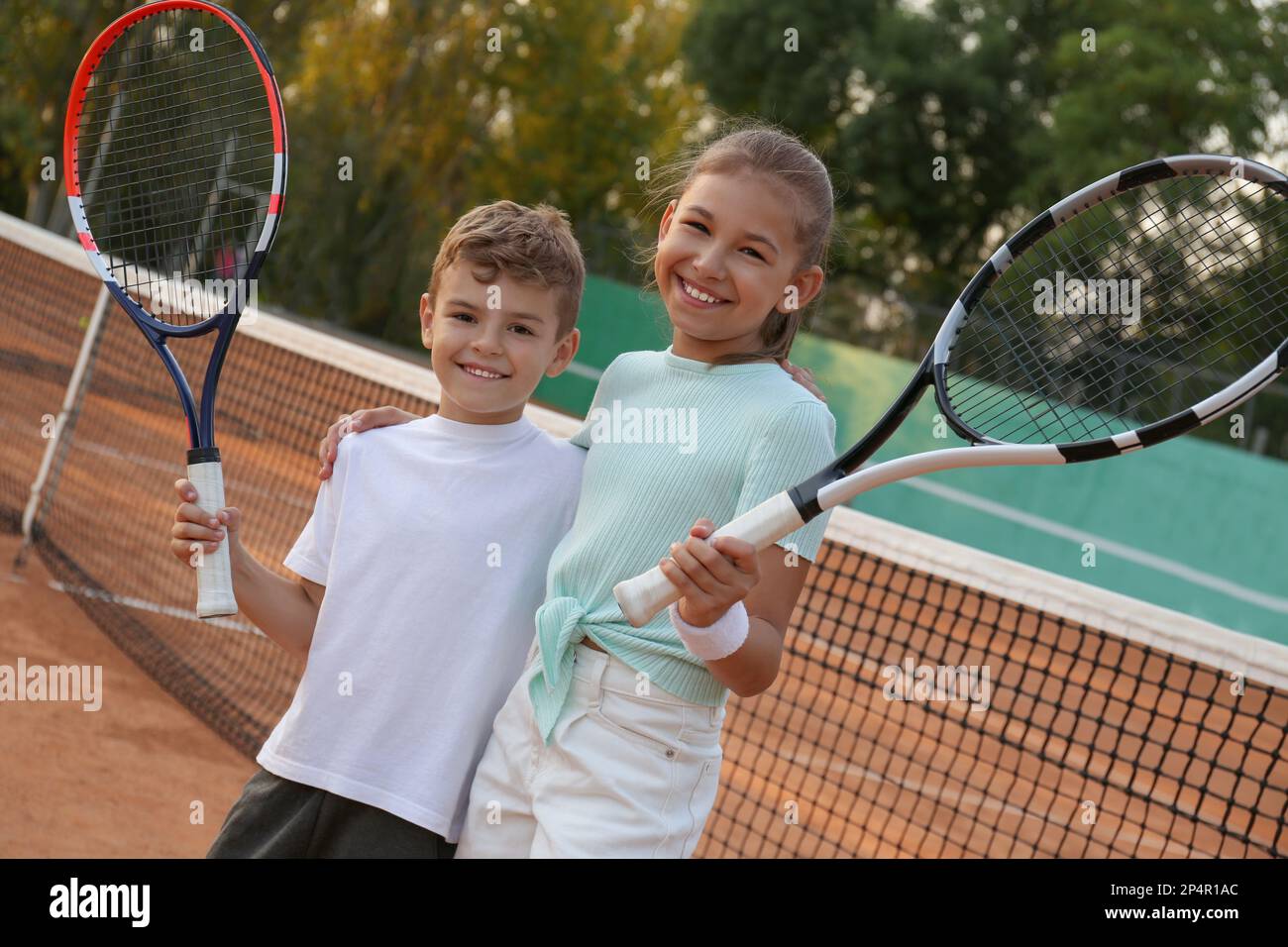 Happy children with tennis rackets on court outdoors Stock Photo - Alamy