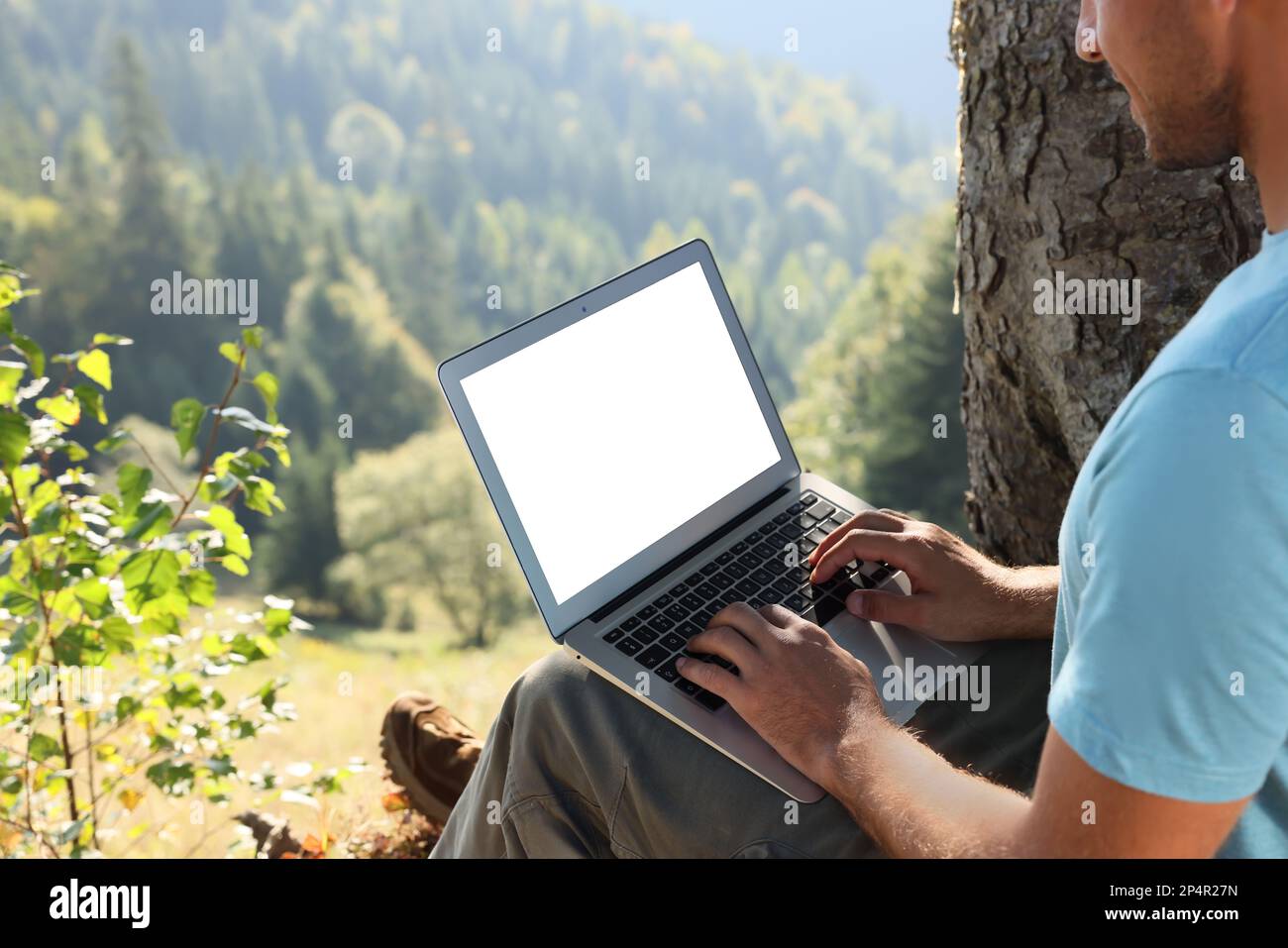 Man working on laptop outdoors surrounded by beautiful nature, closeup ...