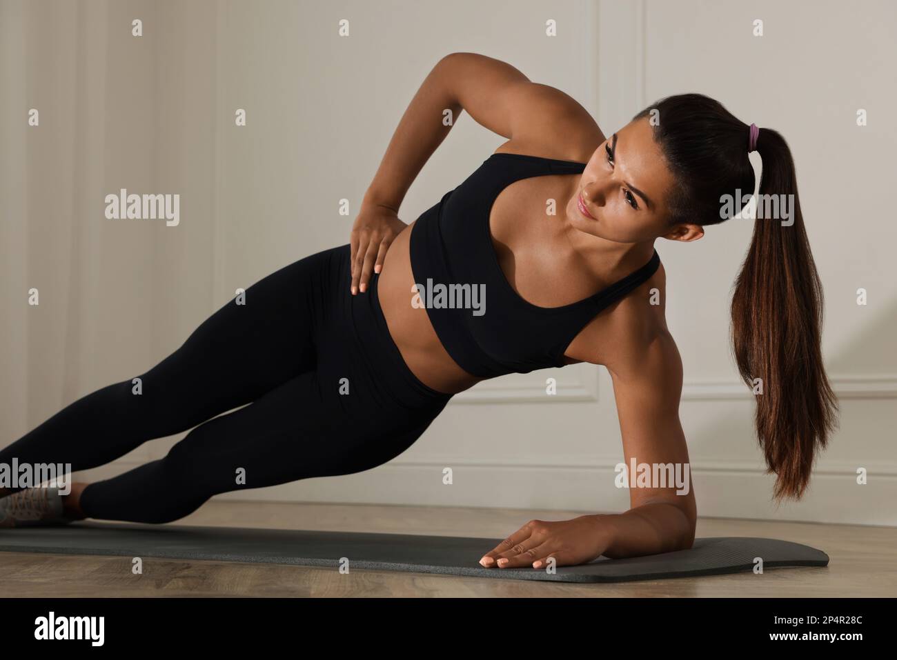 Young woman doing side plank exercise indoors Stock Photo - Alamy