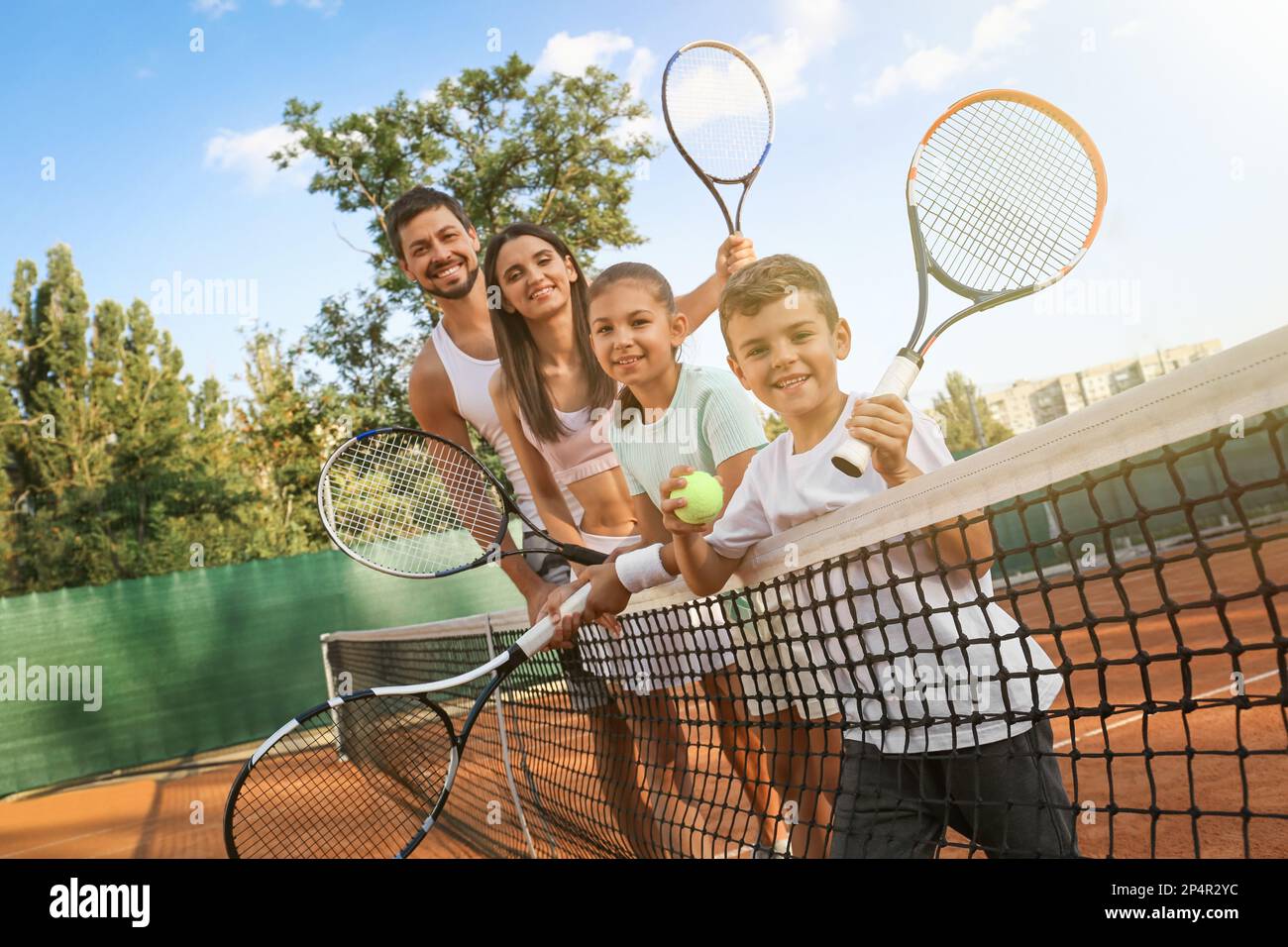 Happy family with tennis rackets on court outdoors Stock Photo - Alamy