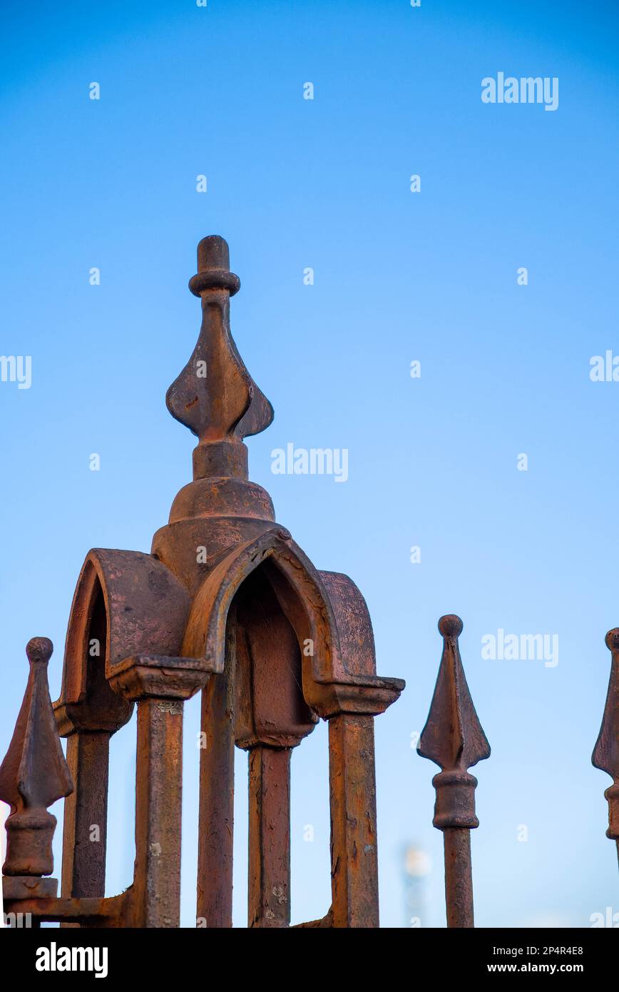 Rusted iron, ornamental gate post with clear blue sky in background ...