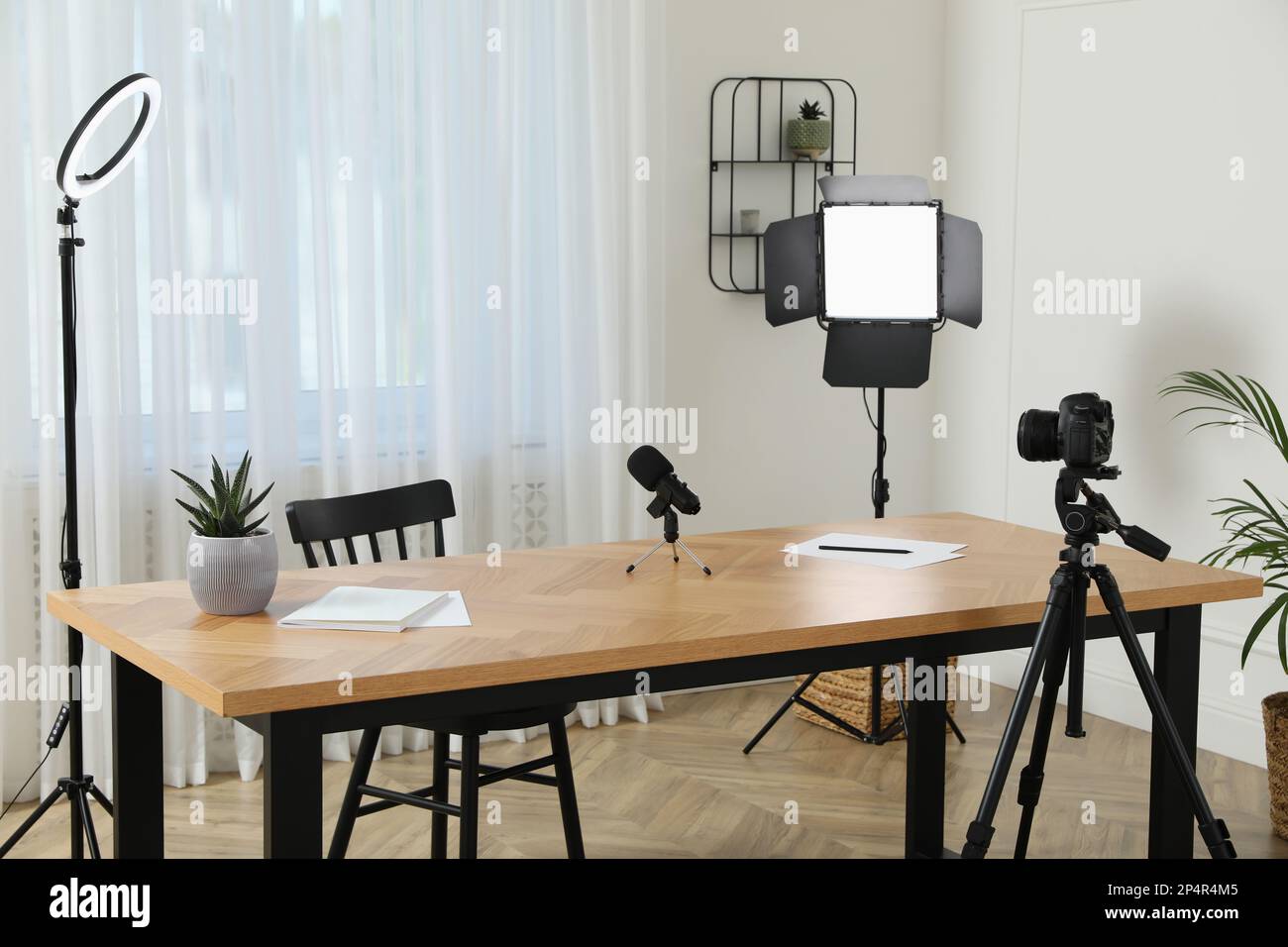 Camera and lighting equipment on tripods near table in room. Blogger ...