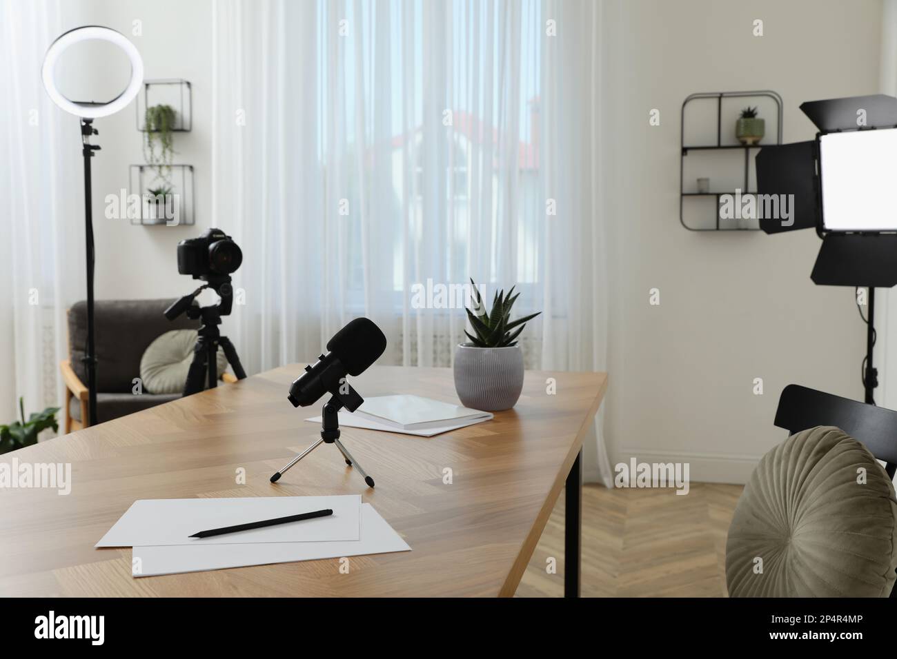 Camera and lighting equipment on tripods near table in room. Blogger ...