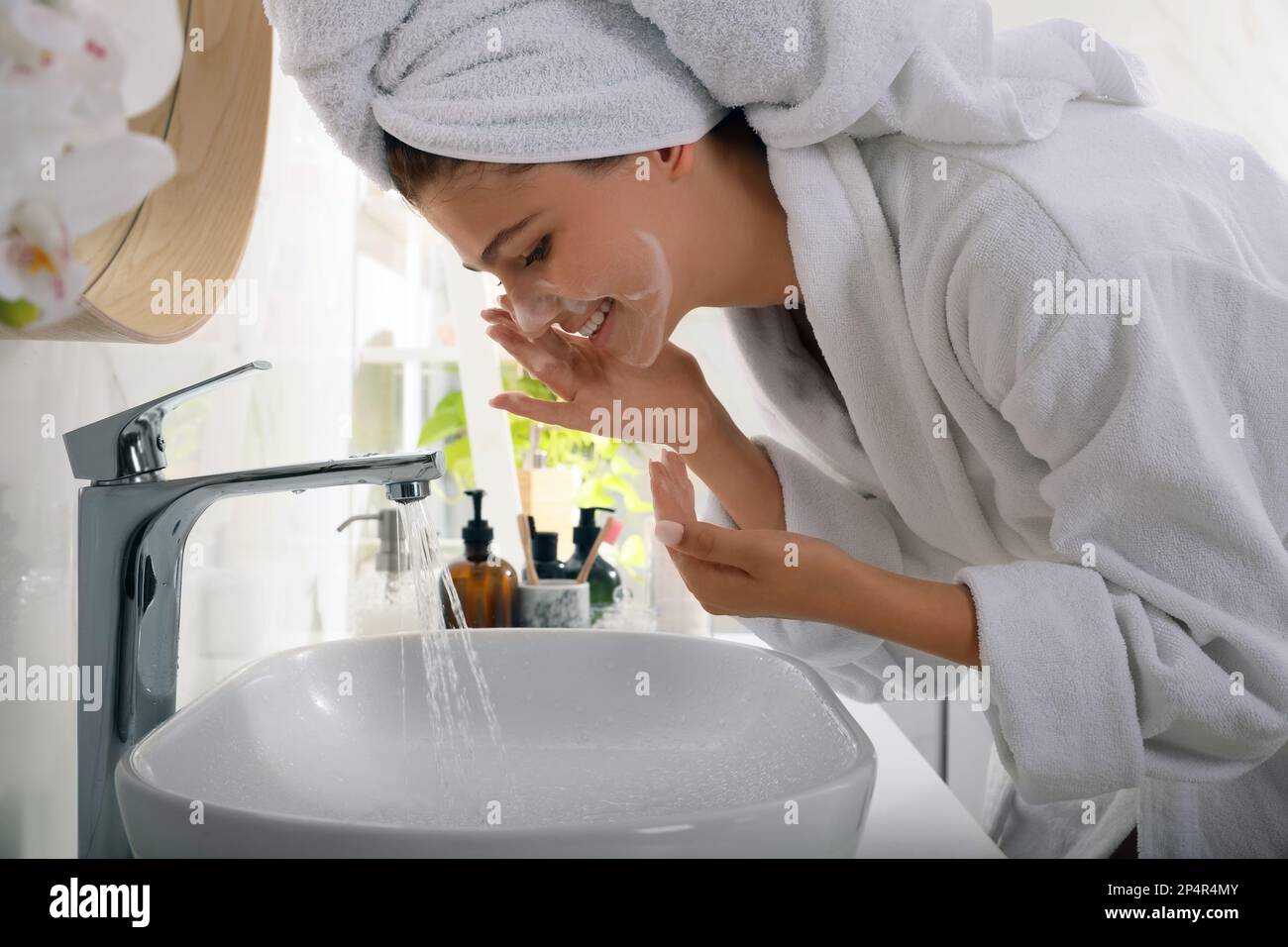Beautiful teenage girl washing face with cleansing foam in bathroom ...