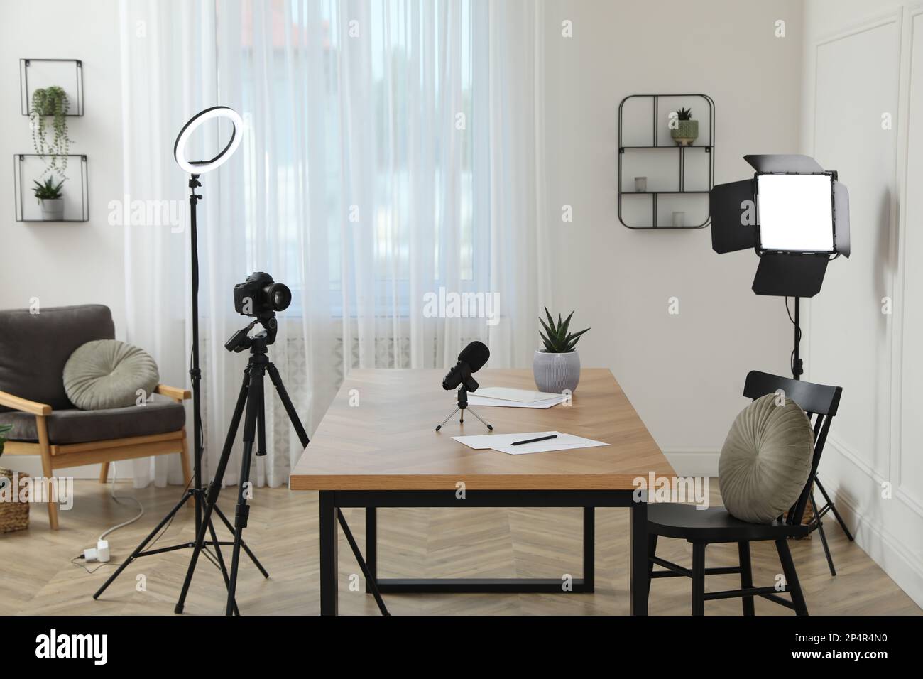 Camera and lighting equipment on tripods near table in room. Blogger ...