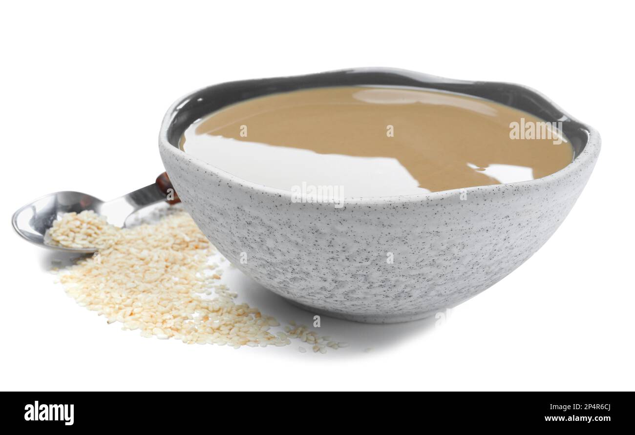 Tasty sesame paste in bowl, spoon and seeds on white background Stock ...