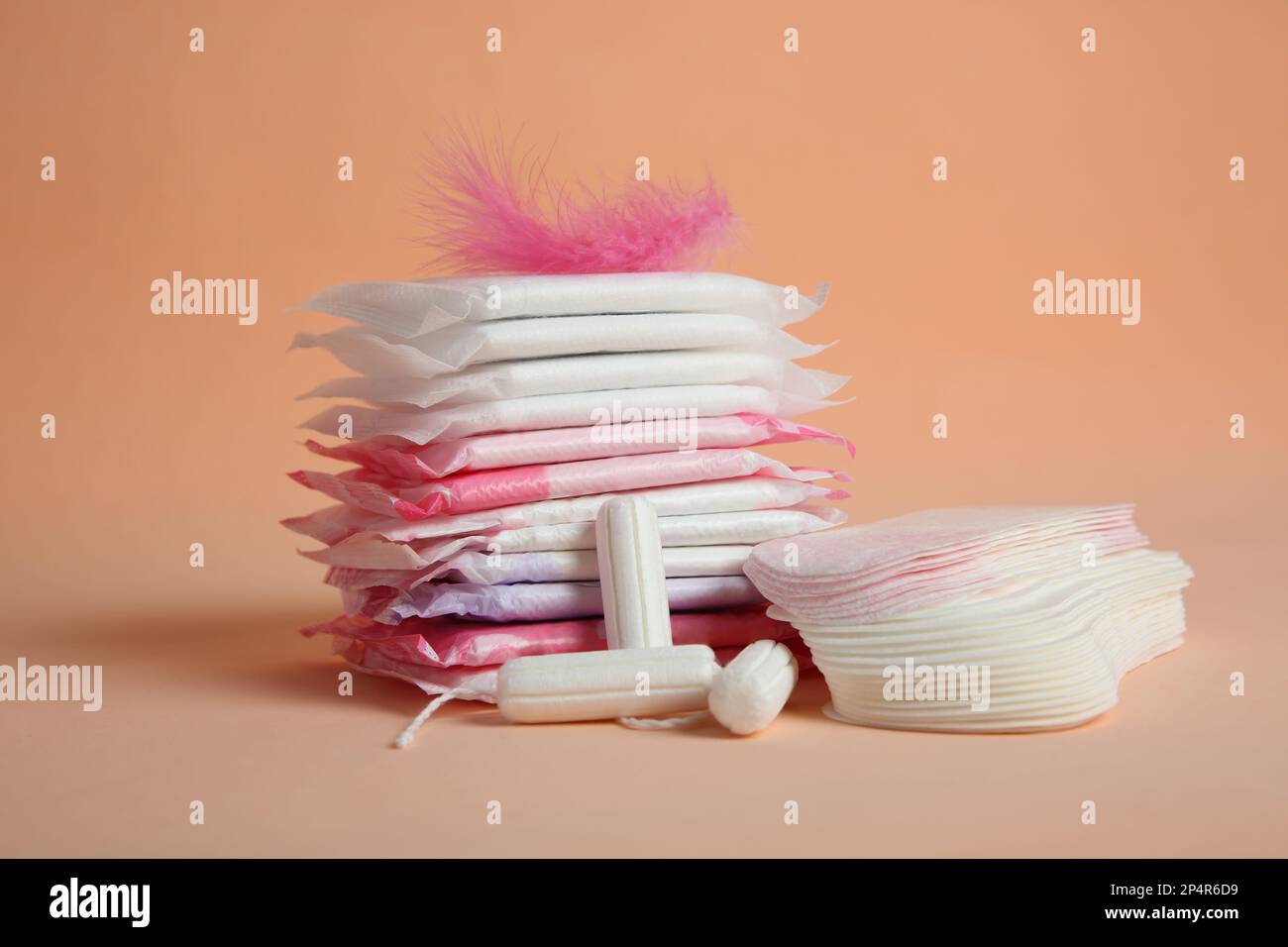Menstrual pads with pink feather and other period products on pale ...