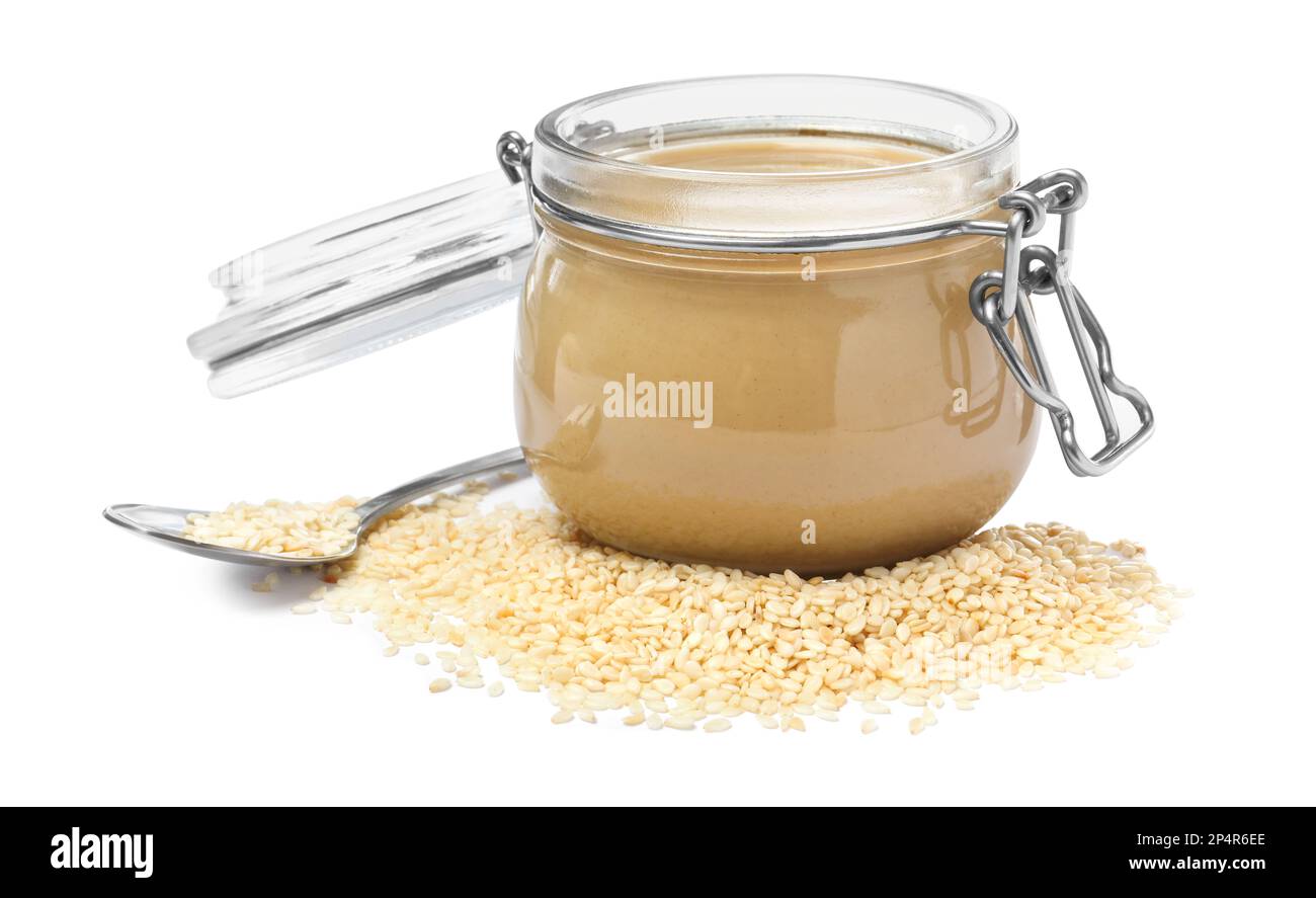 Tasty sesame paste in jar, spoon and seeds on white background Stock ...