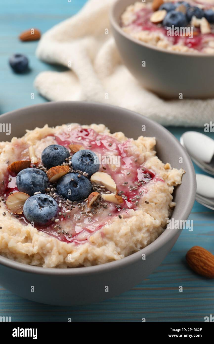Tasty oatmeal porridge with toppings on light blue wooden table ...