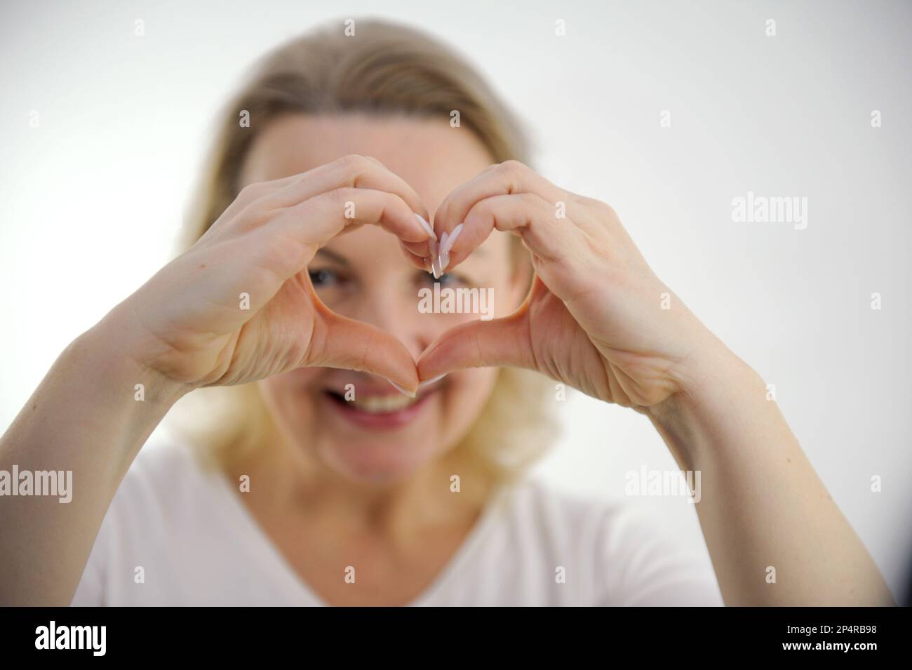 woman shows her heart with her hands a cheerful look through her hands ...