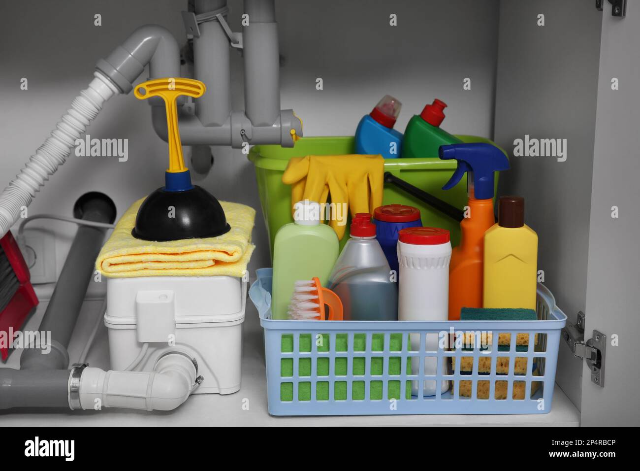 Open under sink cabinet with different cleaning supplies in kitchen ...
