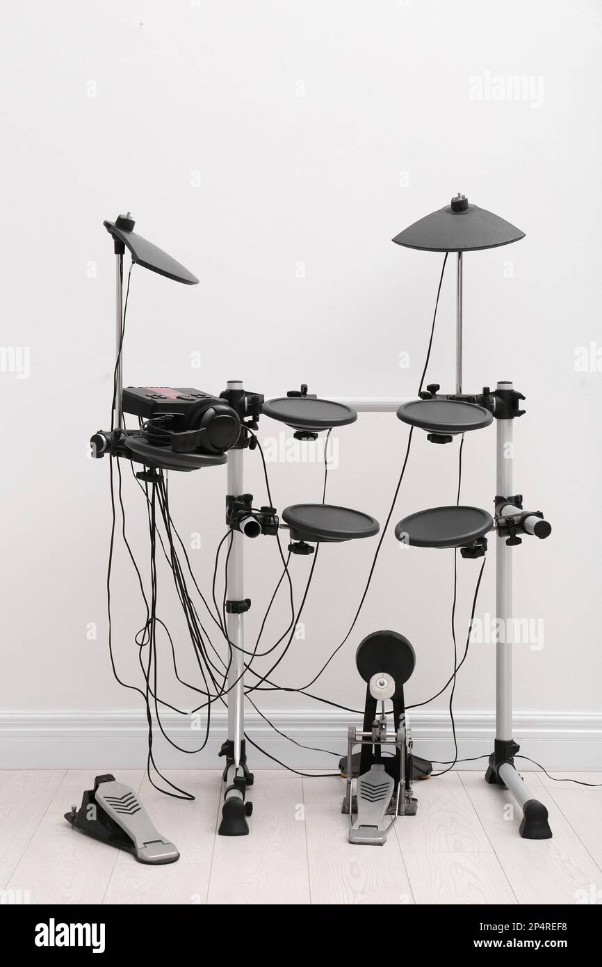 Modern electronic drum kit near white wall indoors. Musical instrument ...