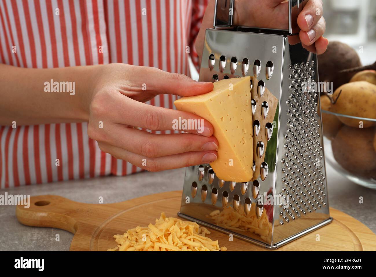 Woman grating cheese at kitchen table, closeup Stock Photo - Alamy