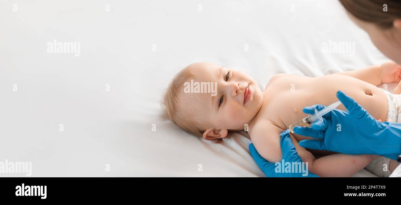Doctor vaccinating smiling baby in clinic. One Year Little baby get an ...