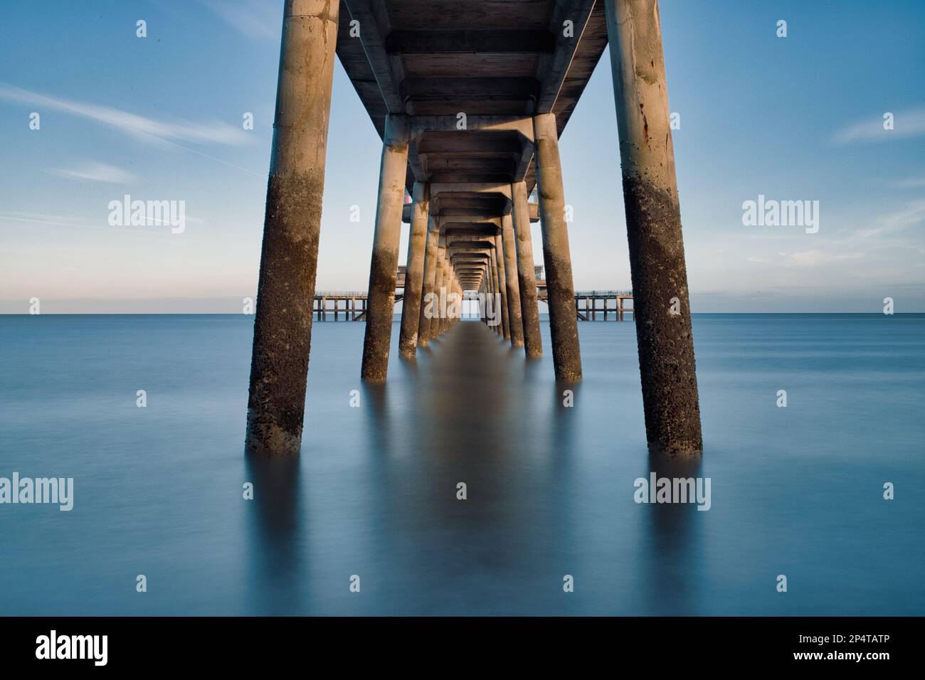 A coastal scene featuring a pier extending out into the horizon, with ...