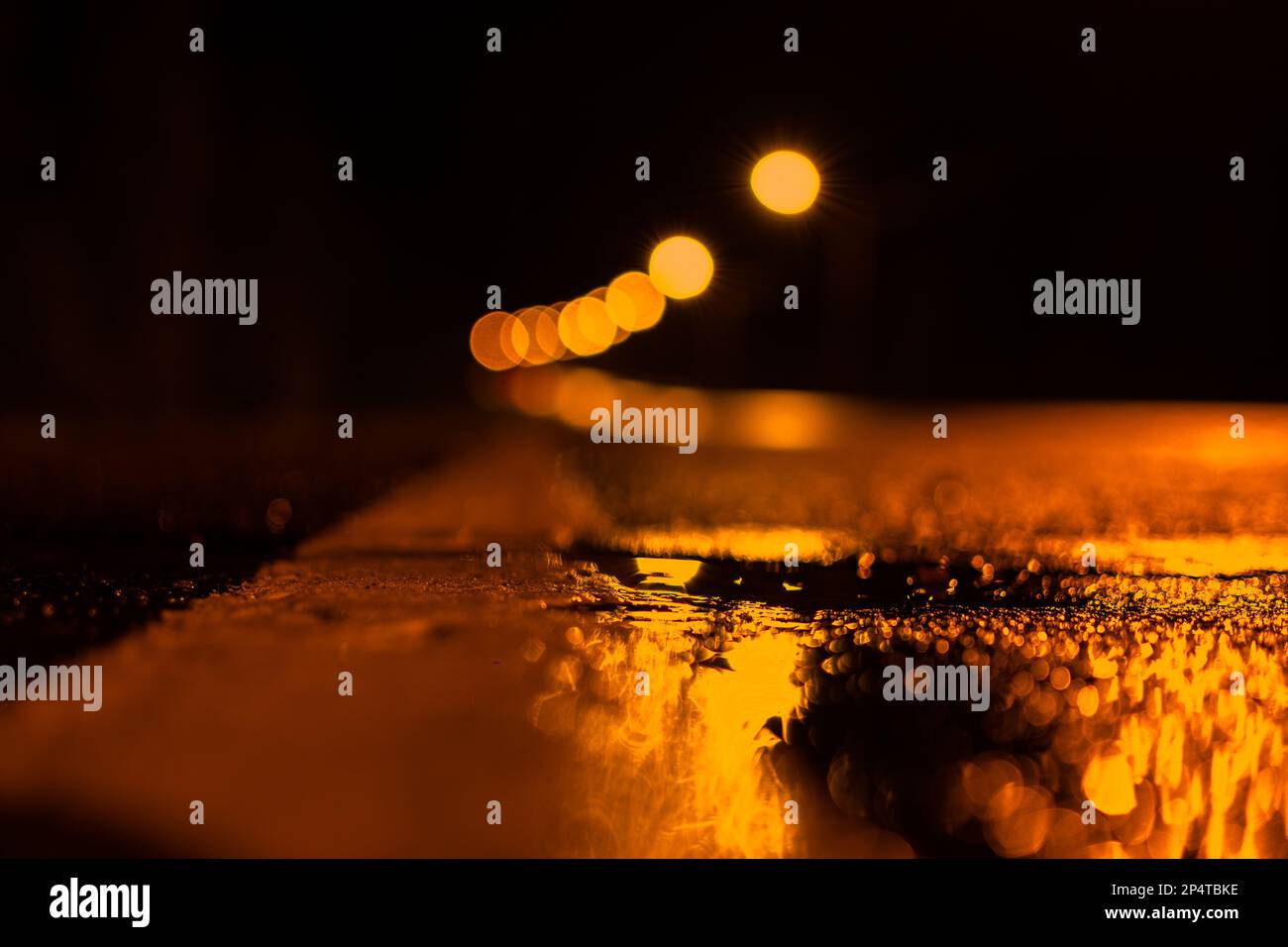 Yellow and orange street lights and wet asphalt. Abstract out of focus ...