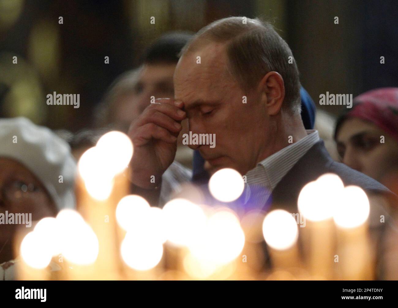 Russia's President Vladimir Putin, center, crosses himself as he ...