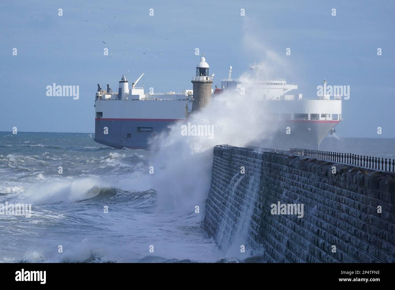 Waves crash over the Tynemouth pier lighthouse as a boat approaches the ...