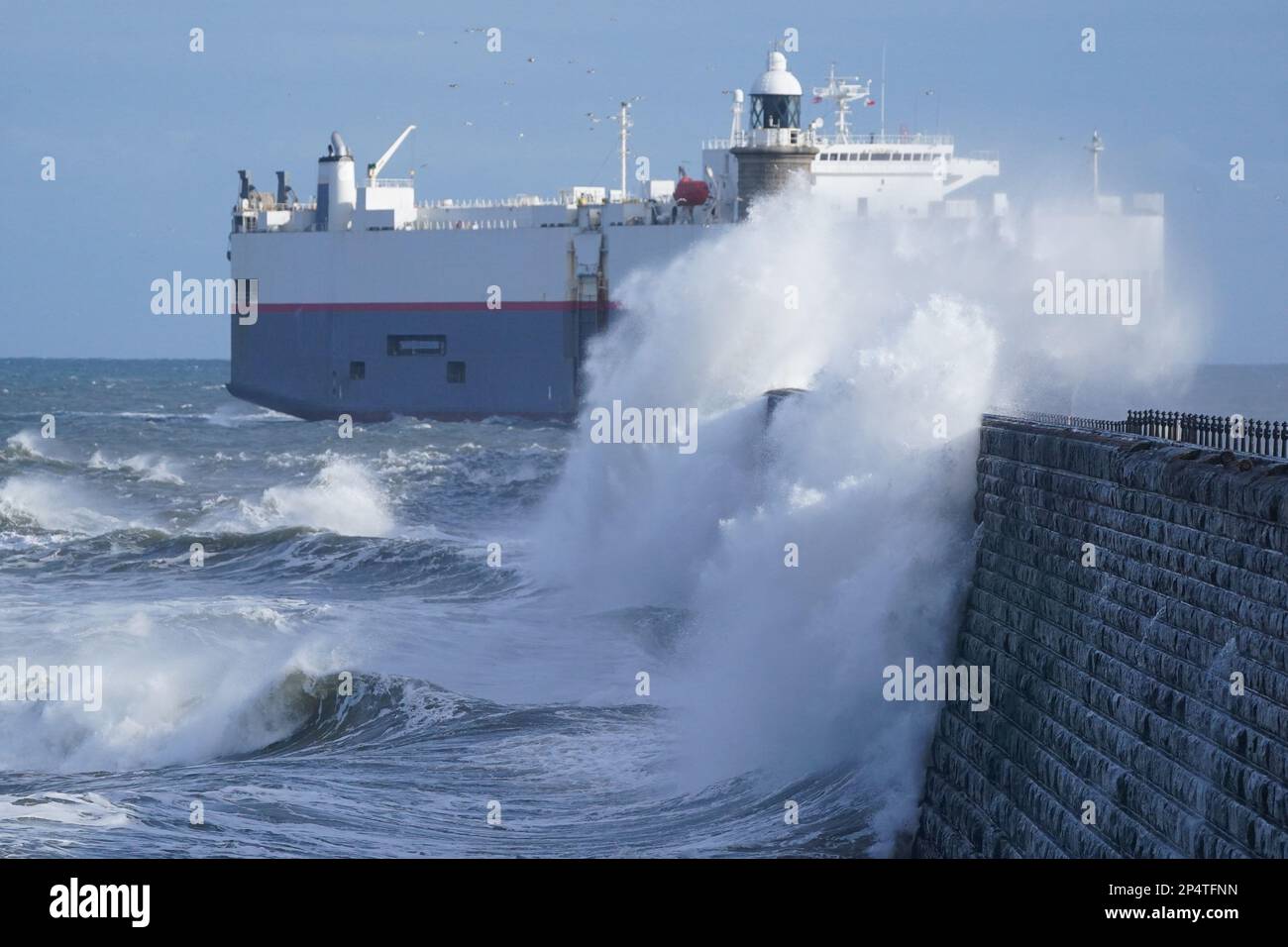 Waves crash over the Tynemouth pier lighthouse as a boat approaches the ...