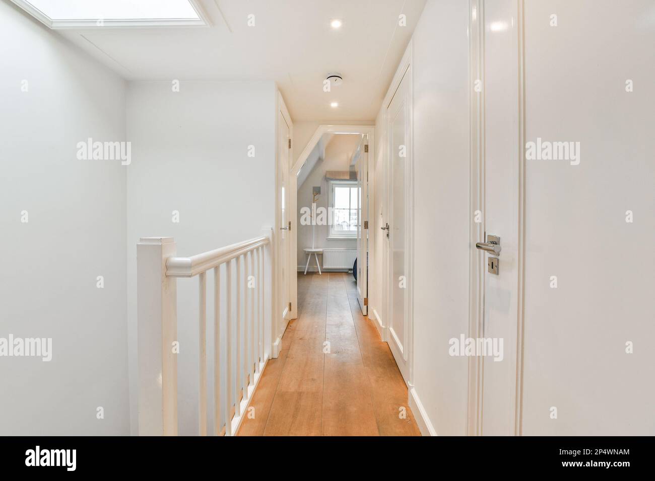 a long hallway with white walls and wood flooring on either side by ...