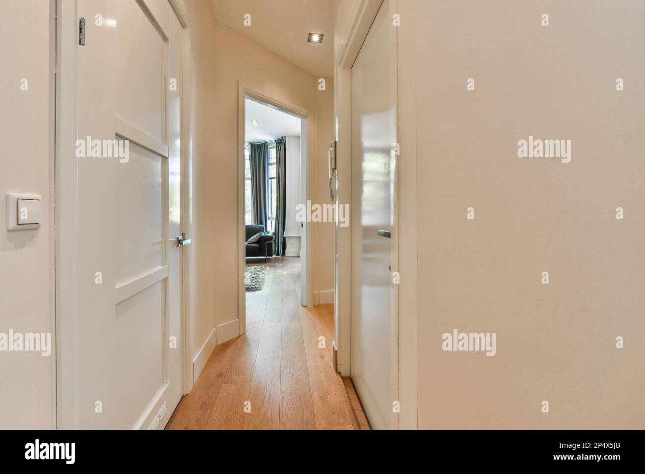 a long hallway with white walls and wood flooring on either side by ...