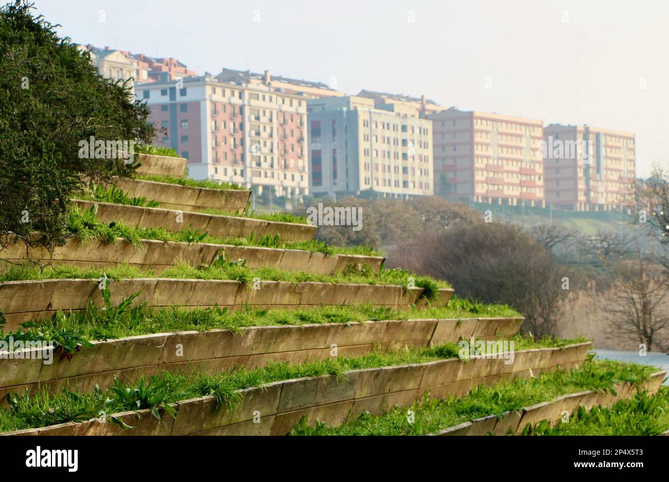 Terraced overgrown planters in a public park with apartment buildings ...