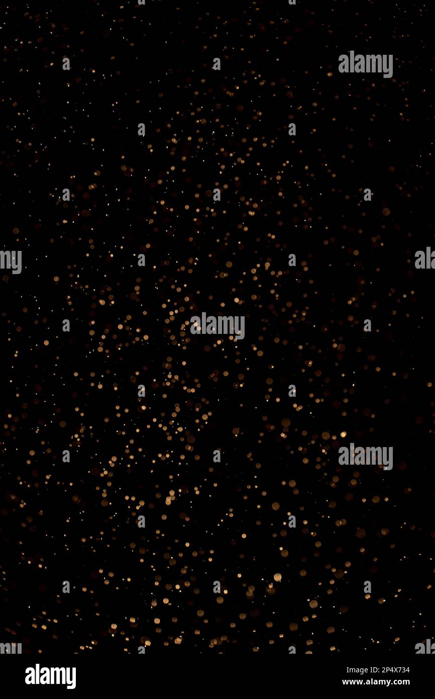 Natural organic dust golden particles floating on a sunbeam on black ...