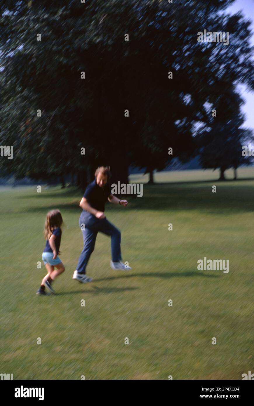 A dad playing with his 5 year old daughter, running about in the park ...