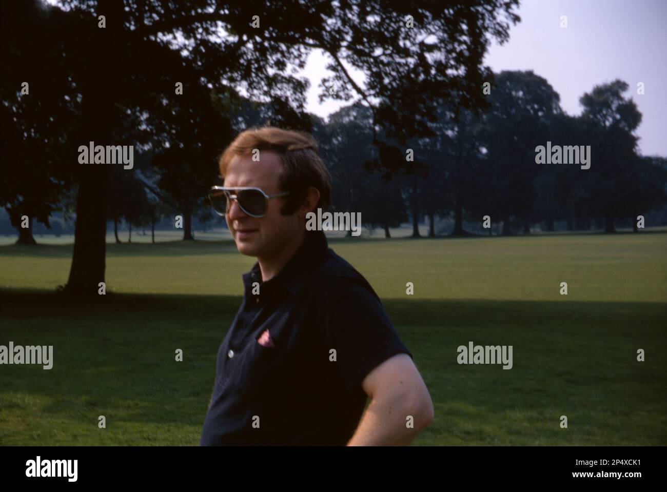 A Dad in his early 30s wearing a dark blue polo shirt and aviator ...