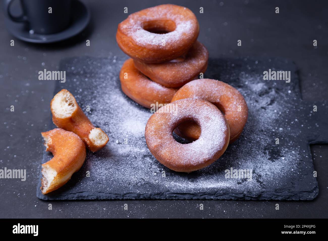 Donuts with powdered sugar and a cup of coffee. Traditional donuts in ...