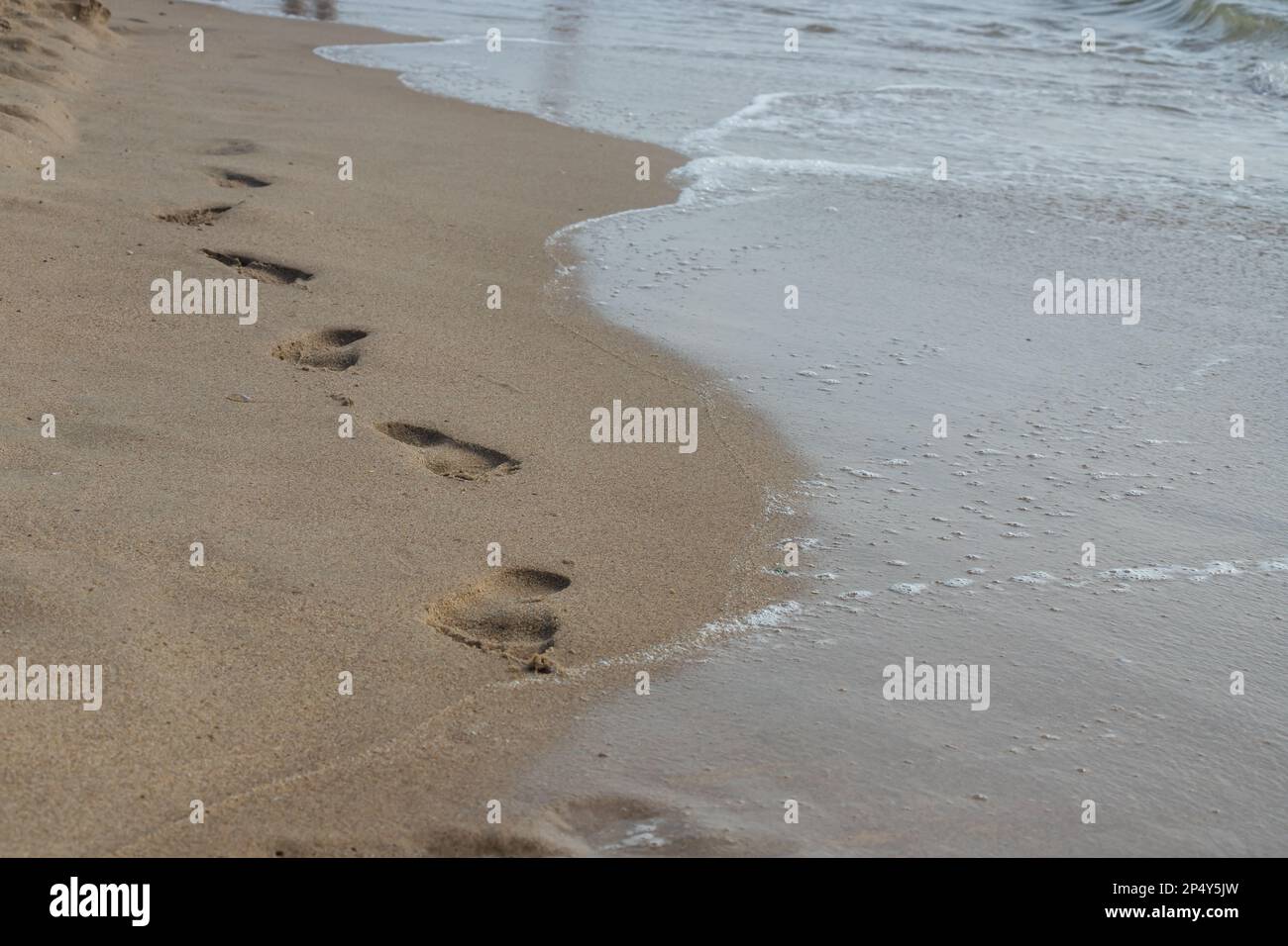 Footprints in the sand beach. Footprints in the sand against a sea wave ...