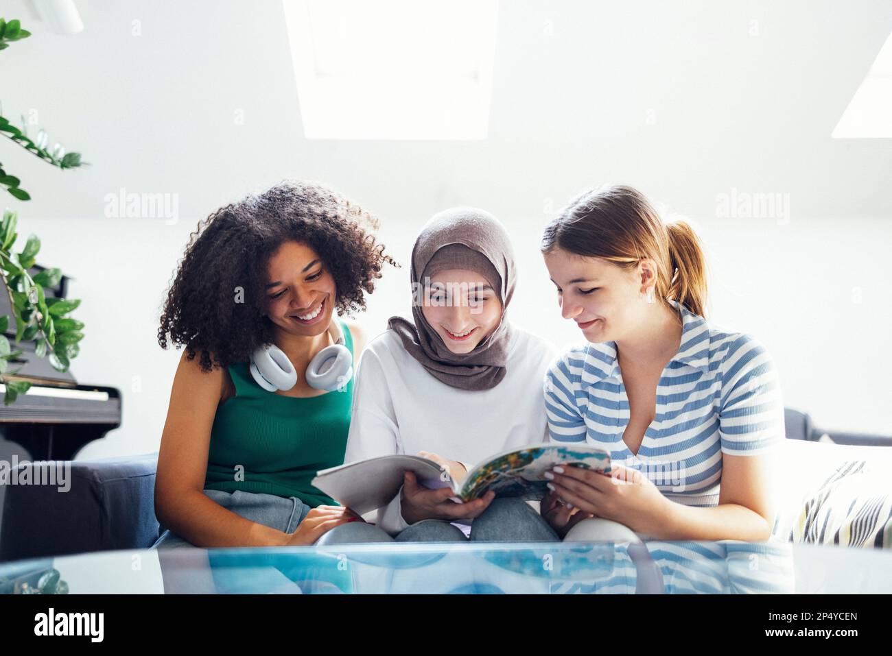 Three pretty female teenagers of different nationalities are reading a ...