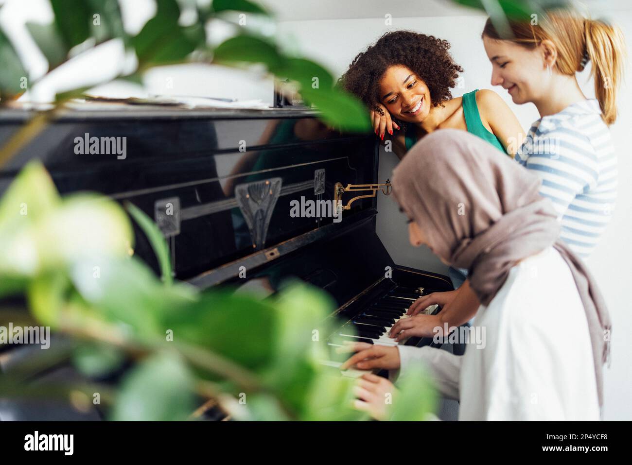 Cute smiling female teenagers play duets on the old piano. Caucasian ...