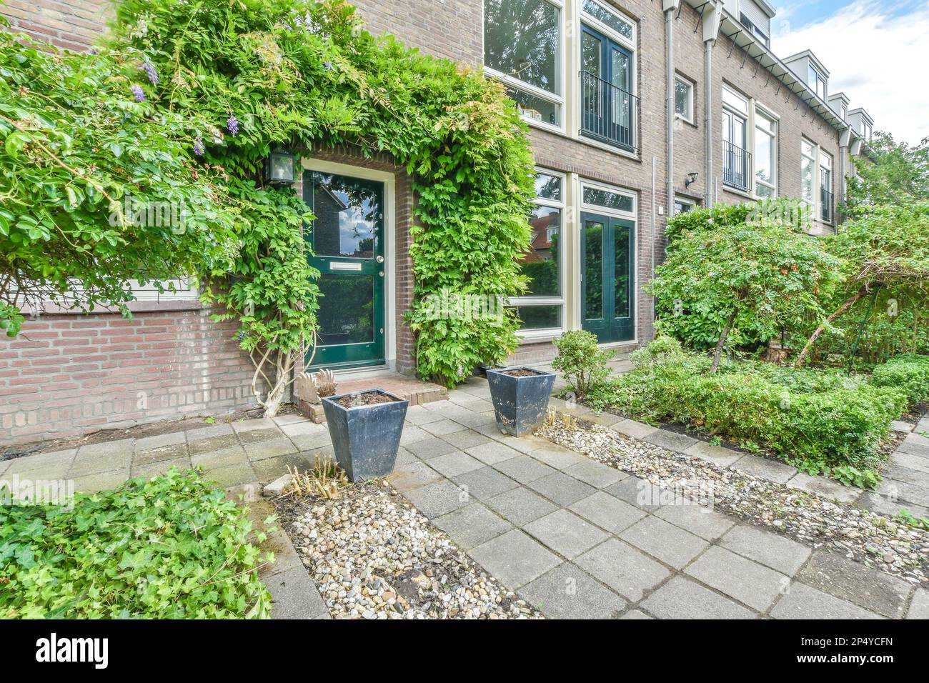 some plants and trees in front of a brick building with green foliages ...