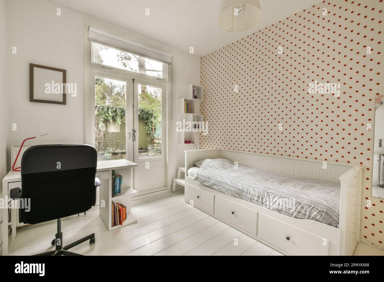 a bedroom with a bed, desk and computer monitor on the wall in front of ...