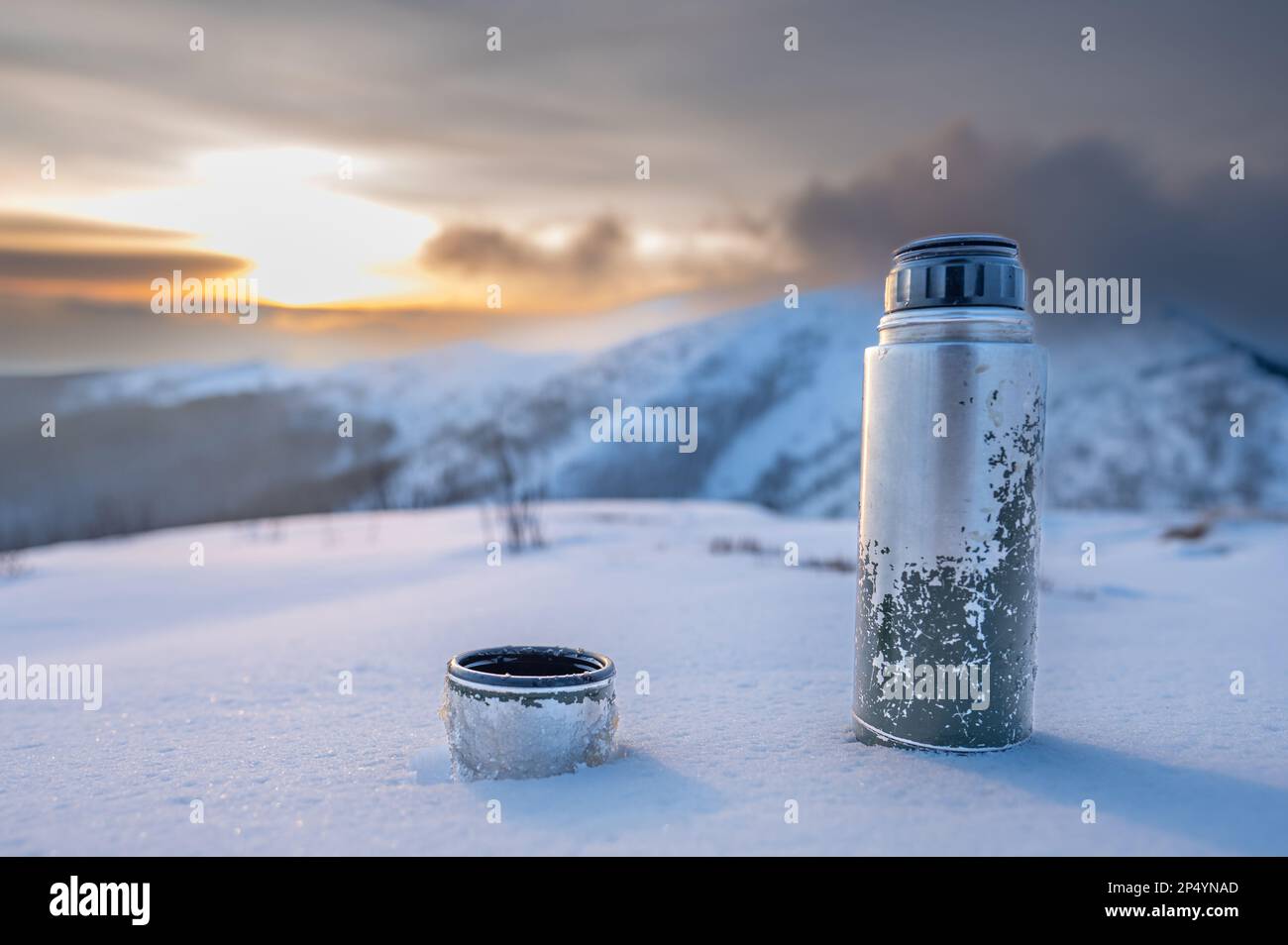 A thermos with a cup of coffee standing on an alpine meadow. Outdoor ...