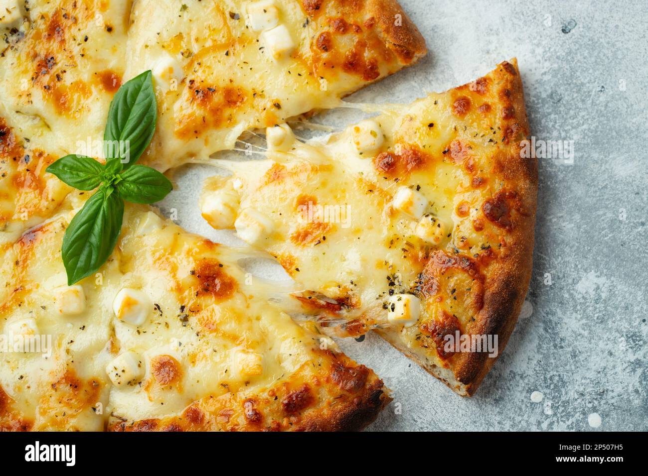 Italian pizza four cheeses with stretching cheese and basil on a light ...