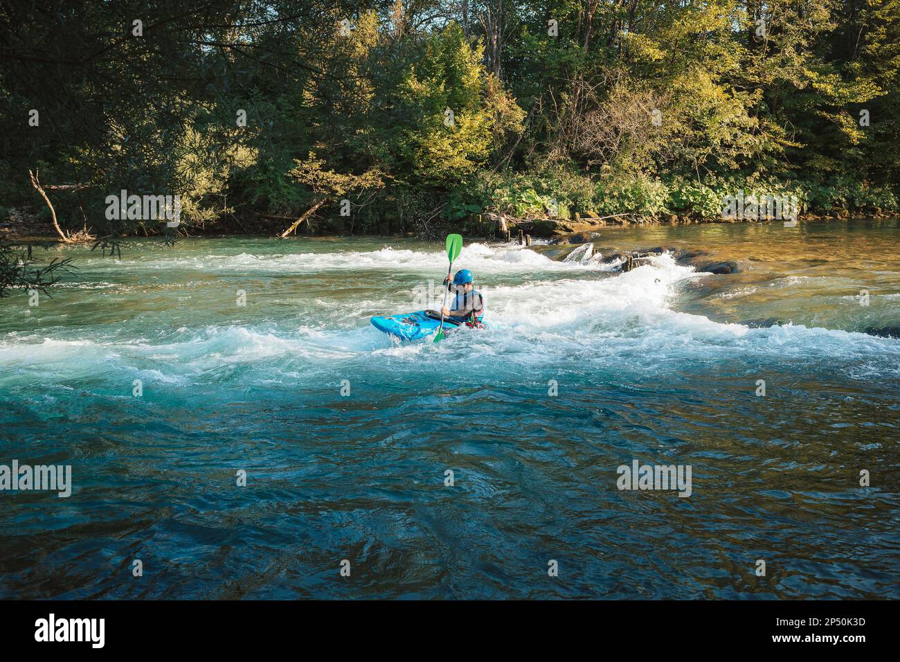 Male recreational athlete paddling carefully over the risky, foamy, and ...
