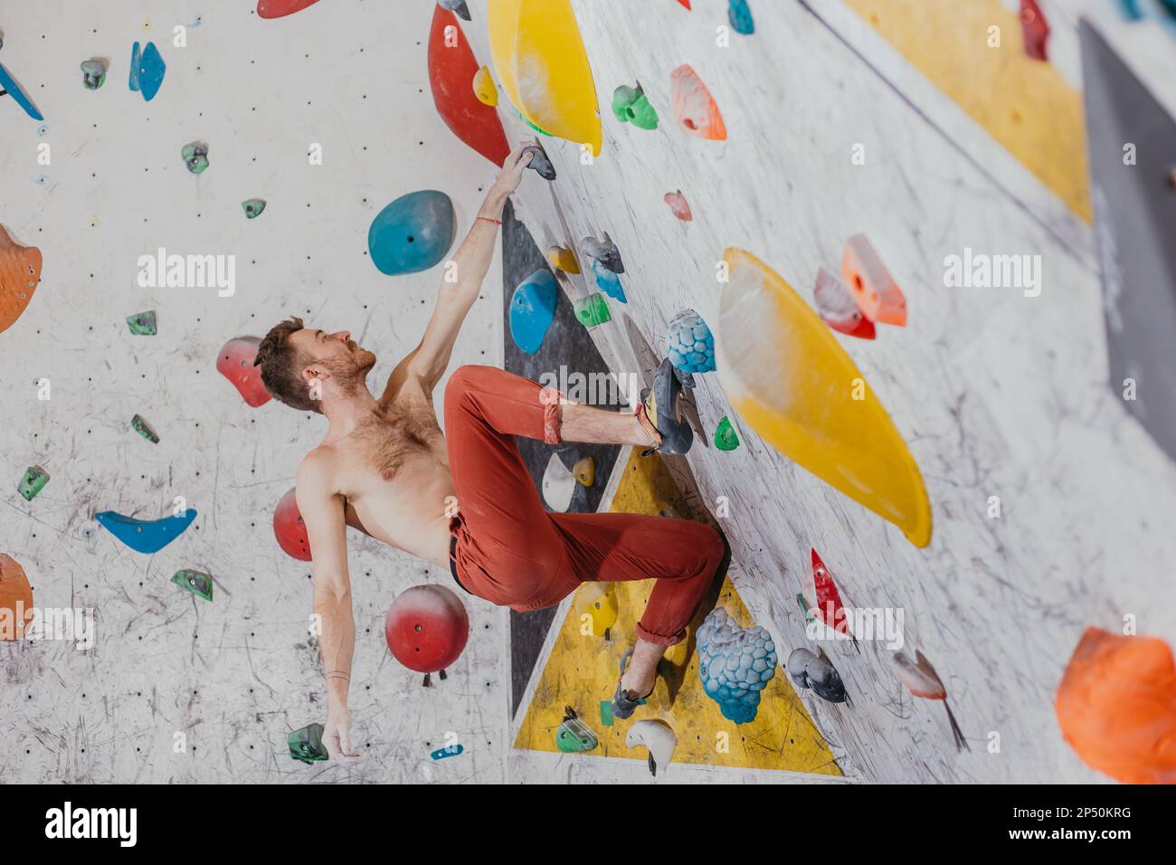 Young climber climbing on the boulder wall indoor, rear view, concept ...