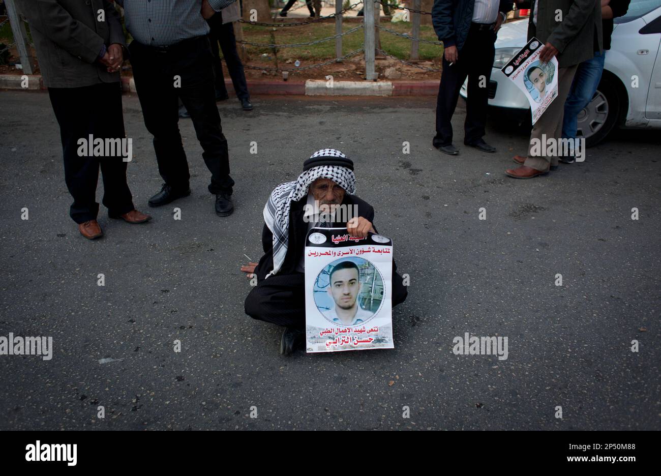 An elderly Palestinian man holds a poster with a picture of late former prisoner Hassan Turabi ...