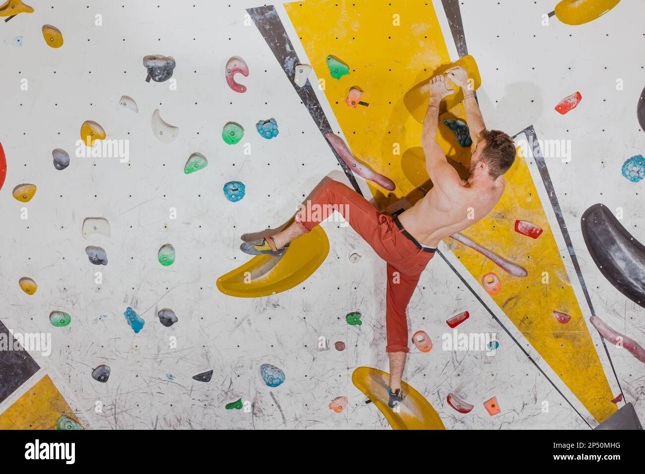 Young climber climbing on the boulder wall indoor, rear view, concept ...