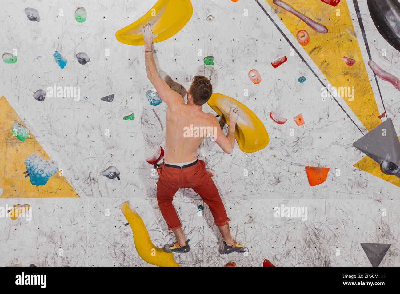 Young climber climbing on the boulder wall indoor, rear view, concept ...