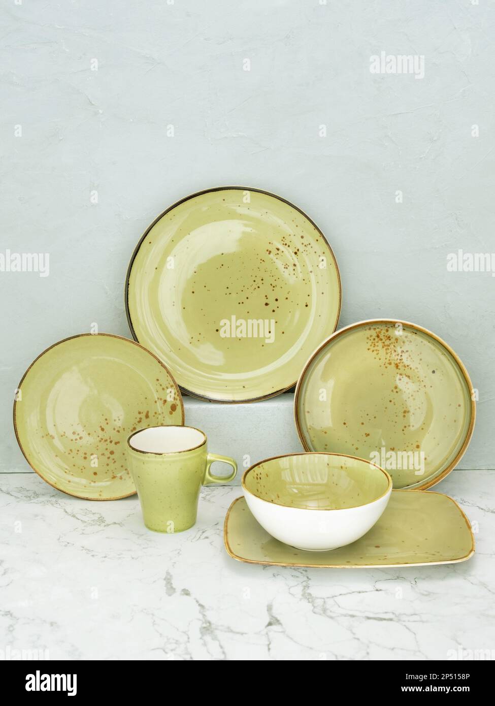 Set of green plates on white marble table with gray background ...