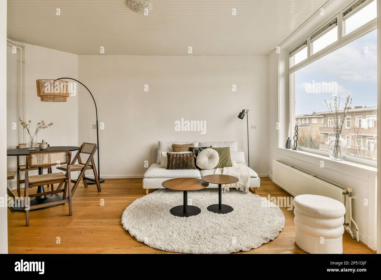 a living room with wood floors and white walls, including a round rug ...
