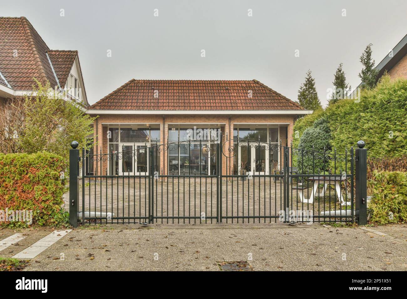 a house with a gate and some bushes in the front yard, as seen from ...