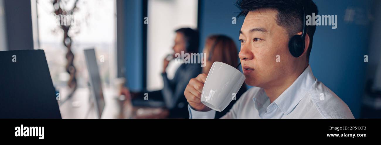 Focused asian businessman drinking coffee while working on computer in ...