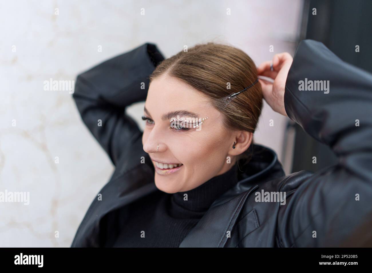 Smiley woman applying instant invisible stickers to the face indoors ...