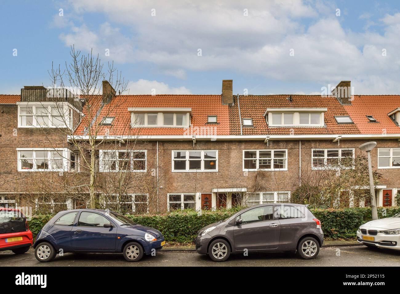 two cars parked in front of a house with red roof tiles on the top and ...