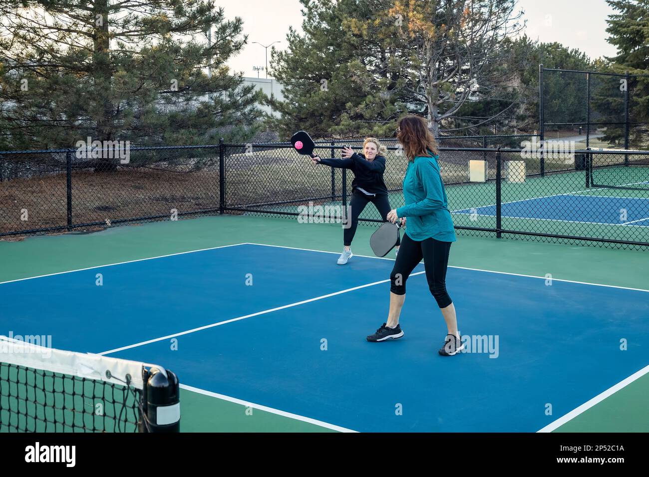 A female pickleball player returns a serve on a blue and green court as ...